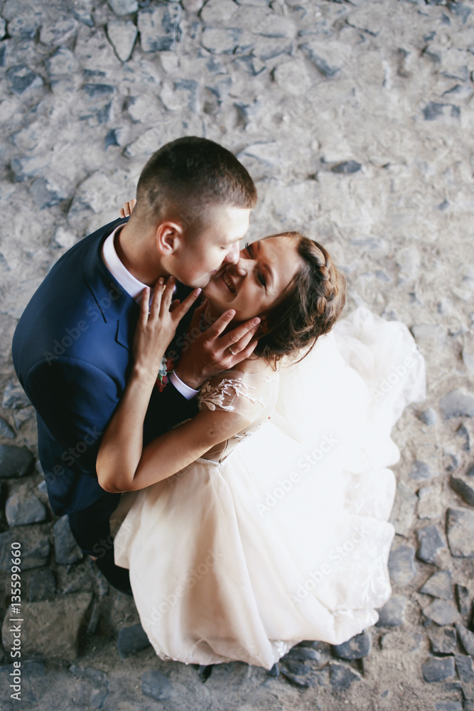 Groom bends smiling bride over kissing her neck Photos | Adobe Stock