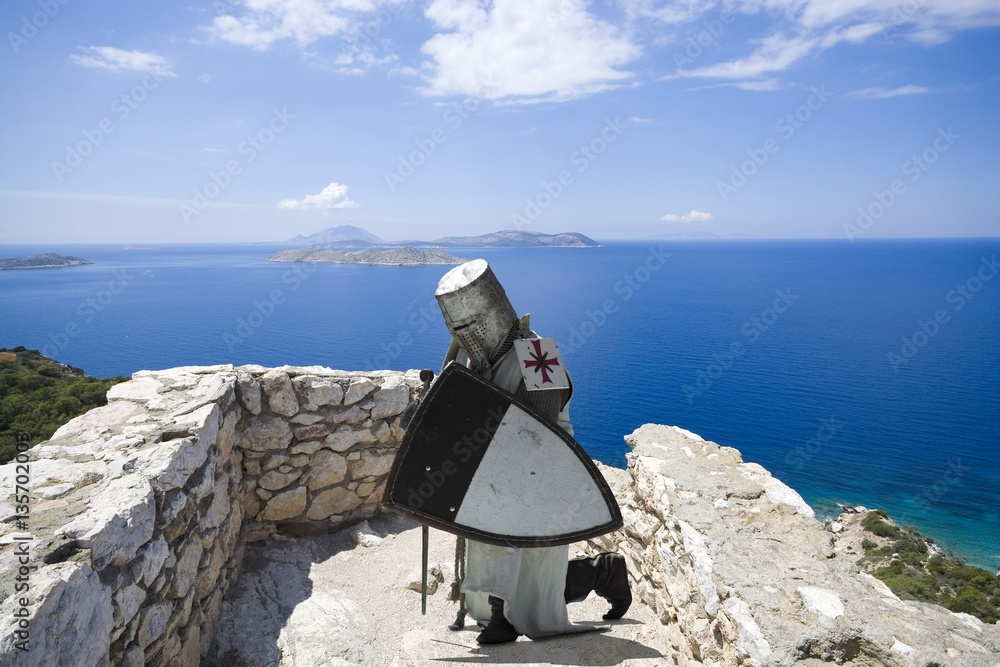 Medieval knight praying in ruined castle built by the Knights of Saint ...
