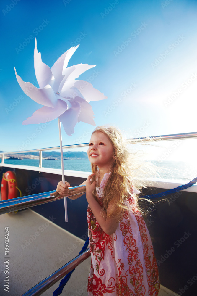 Foto Stock Cute blonde small girl playing with pinwheel on cruise ship ...