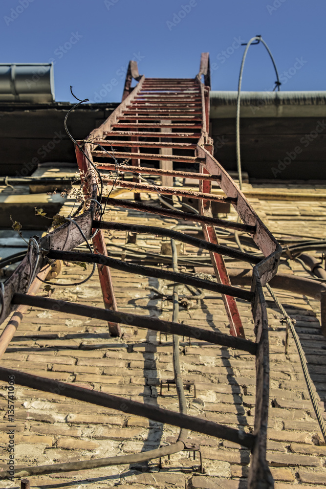 Damaged,deformed metal ladder on the side of an old industrial building ...