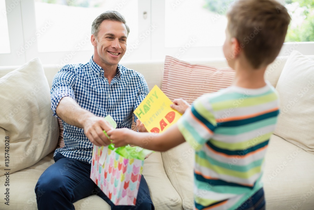 Father receiving a gift from his son in living room Stock-Foto | Adobe ...