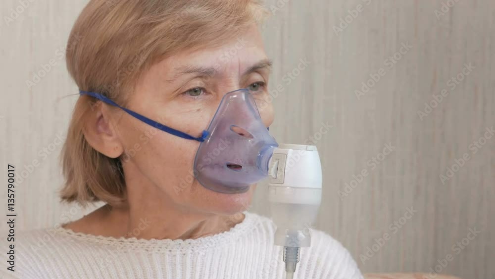 Senior woman holding a mask from an inhaler at home. Treats ...