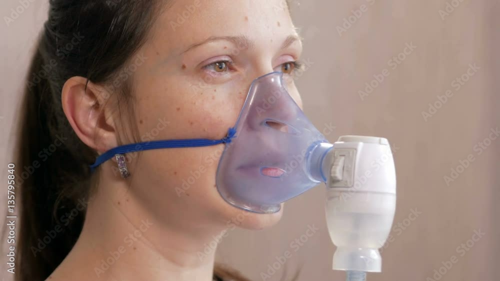 Young woman holding a mask from an inhaler at home. Treats inflammation ...