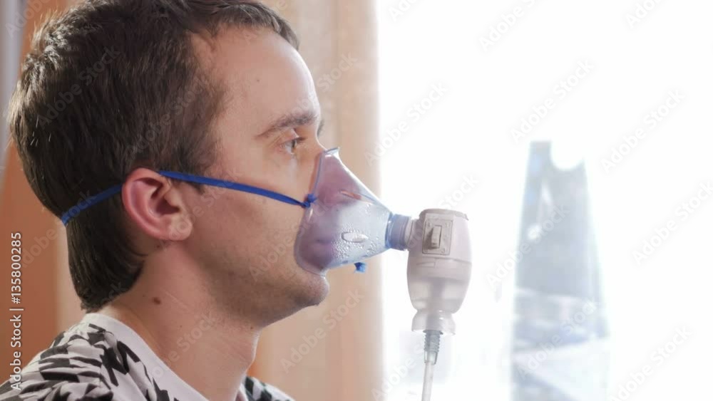 Young man holding a mask from an inhaler at home. Treats inflammation ...