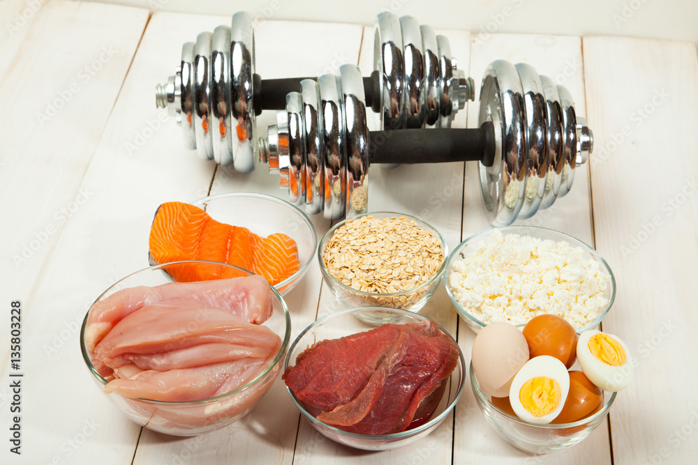 Protein diet, fish, cheese, eggs, meat, chicken and dumbbells on a ...