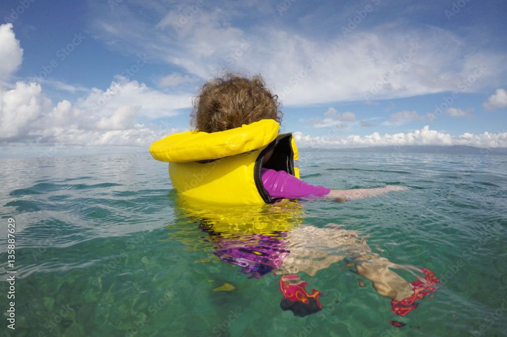 Poster Little child floating with a life jacket alone in the ocean ...