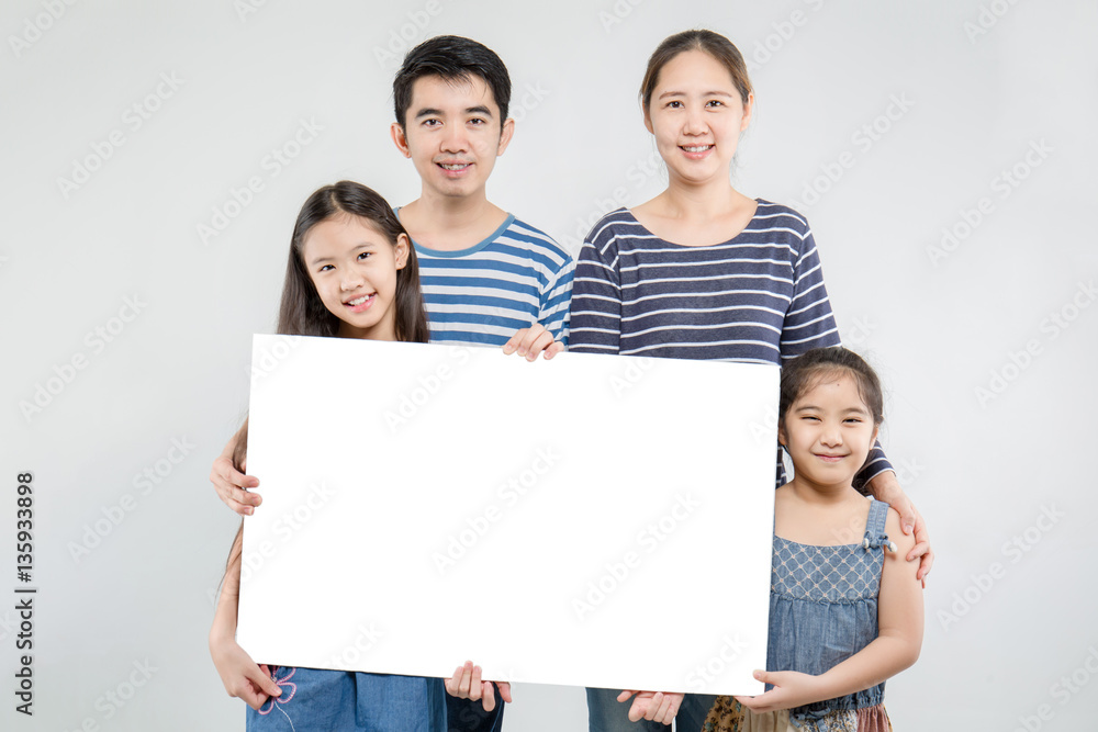 Smiling happy Asian family with big white poster on isolated background ...