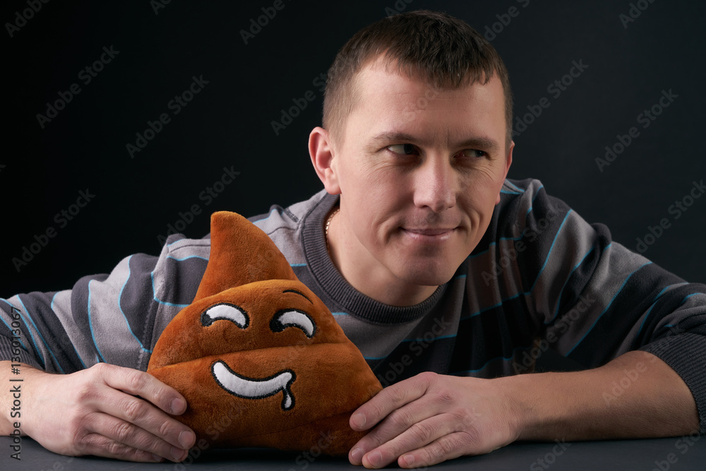 Shit toy in man hands.Poop emoticon on black background. Stock Photo ...