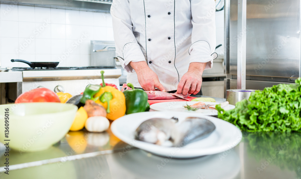 Koch bereitet Zutaten wie Gemüse und Fisch zum Kochen in seiner Küche ...