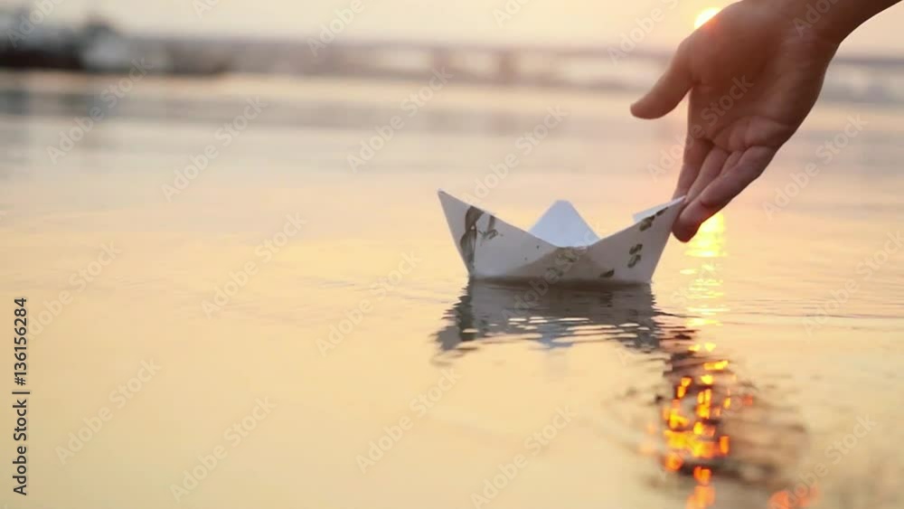 Man's hand launches paper boat on the water and pushing it away during ...