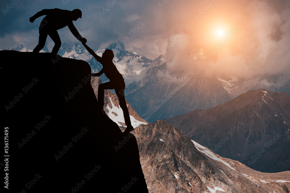 Male and female hikers climbing up mountain cliff and one of them ...
