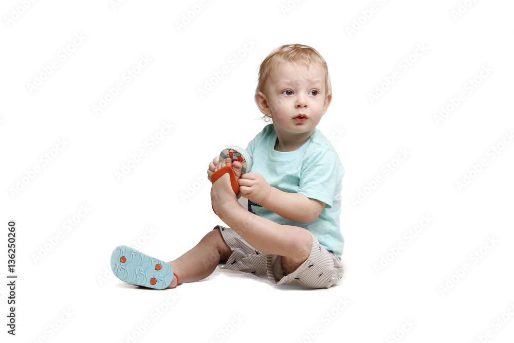 Cute little baby boy sitting on the floor and holding his leg isolated ...