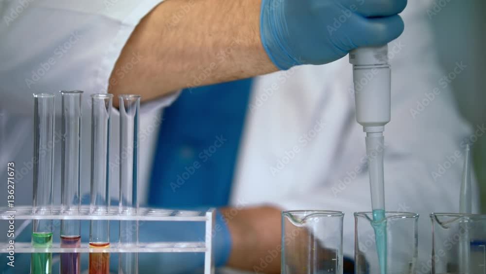 Scientist hands pouring liquid samples into test tubes. Close up of ...