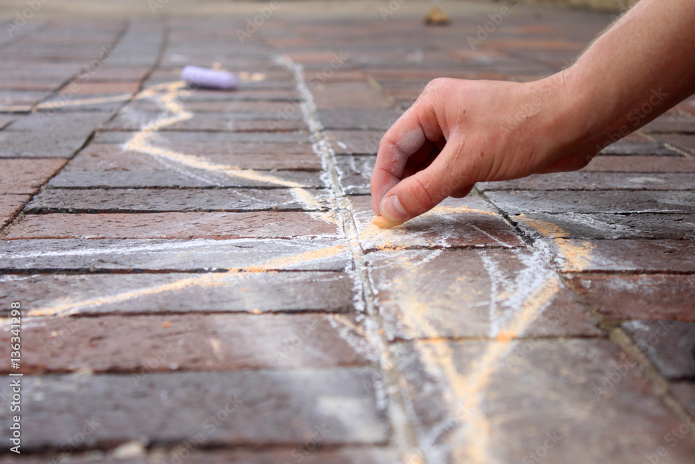 a hand busy drawing with chalk on a pavement Stock Photo | Adobe Stock