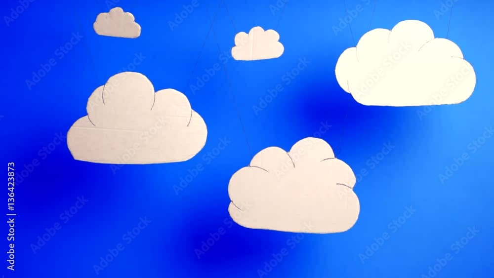 Moving white cloud cardboard cutouts hanging in front of blue sky ...