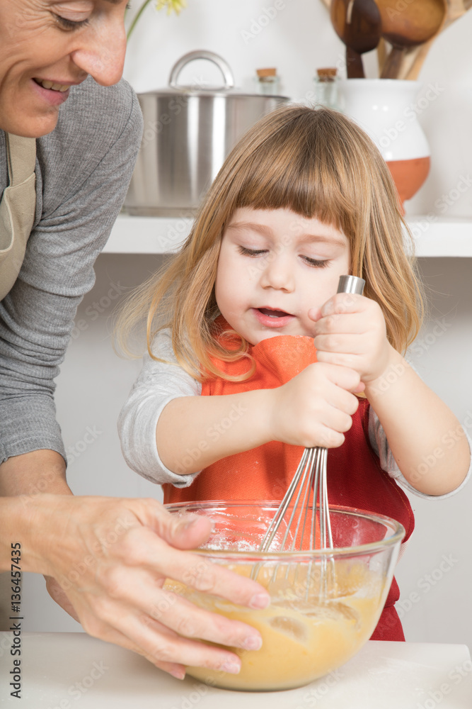 three years old child whipping cream in glass bowl with metal whisk ...