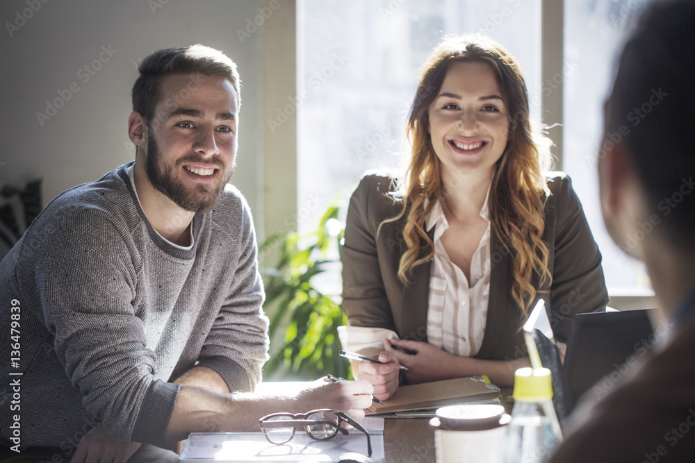 Smiling friends sitting at table in classroom Stock Photo | Adobe Stock