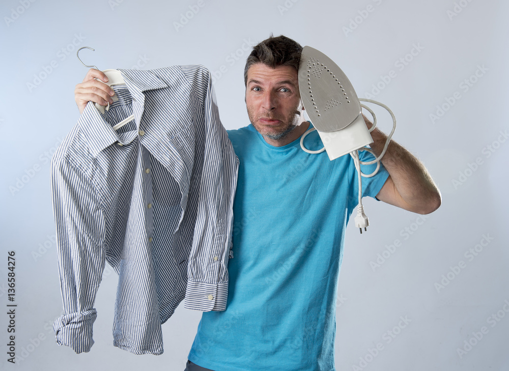 young attractive and frustrated man holding iron and shirt stressed and ...