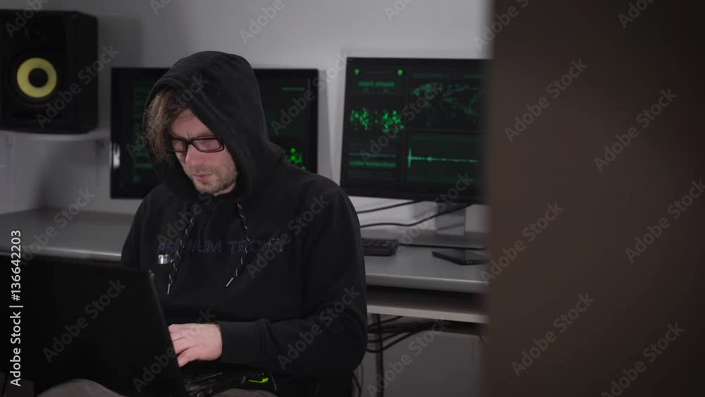Video Stock Pleased Hacker in a black hoodie with color kayushonom sitting at his natbukom and ...