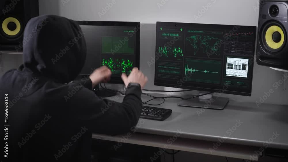 Back view of a hooded angry hacker in black making cyber attack on bank ...