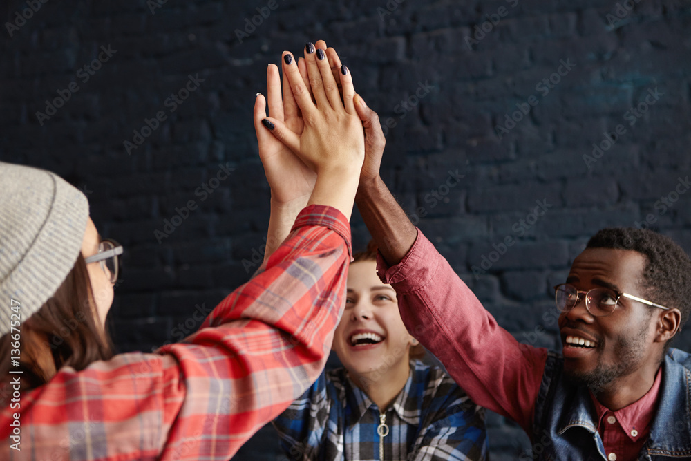 Teamwork and success concept. Three students cheering, giving high five ...