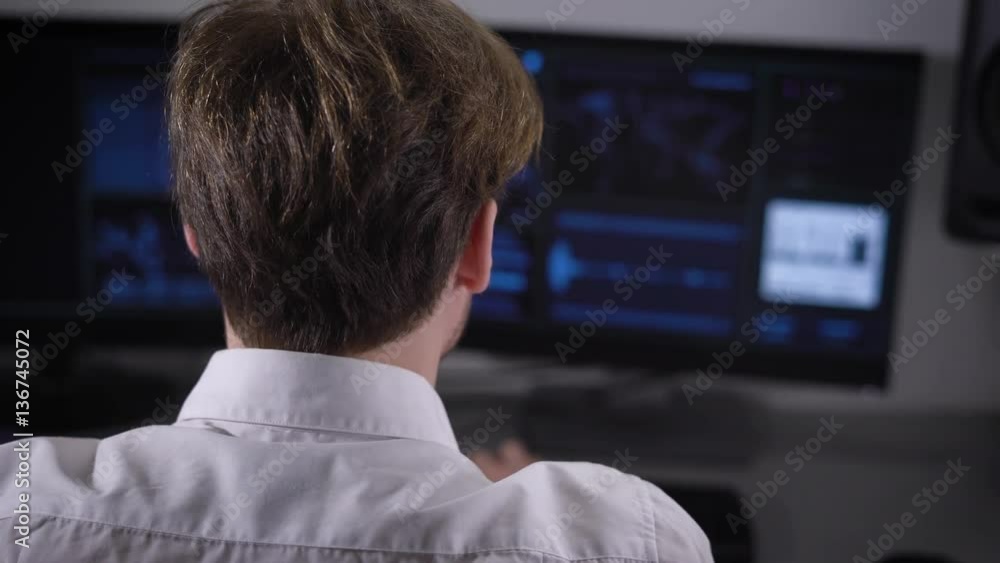 Experienced IT specialist works on a new program on two computers ...