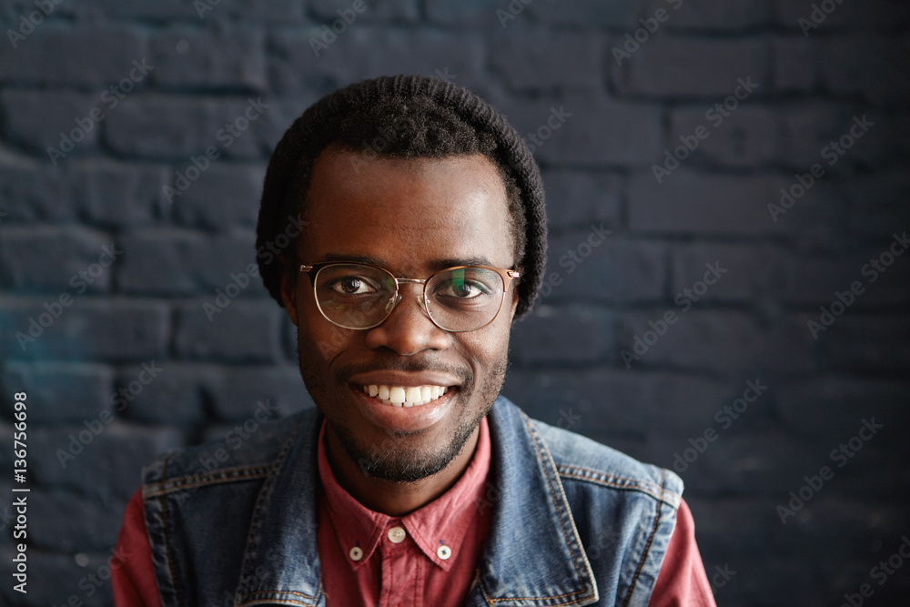 Indoor portrait of happy and cheerful young dark-skinned male student ...