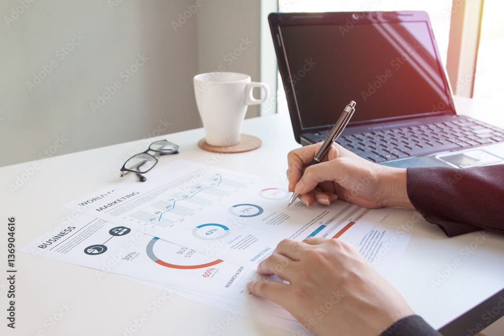 business documents on office table with laptop computer and graph ...