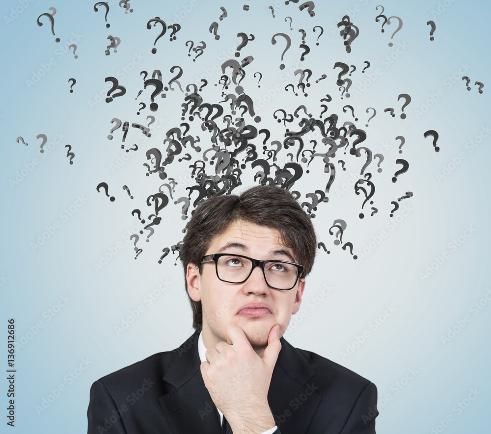 Thinking man in glasses, question marks, gray wall Stock Photo | Adobe ...
