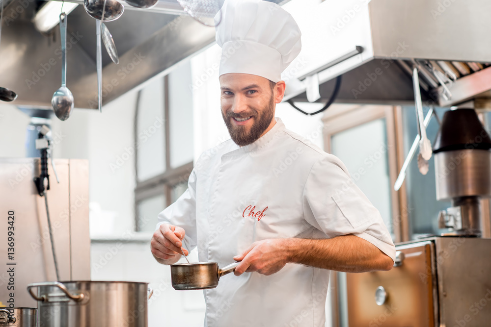Handsome chef cook in uniform cooking food on the gas stove at the ...