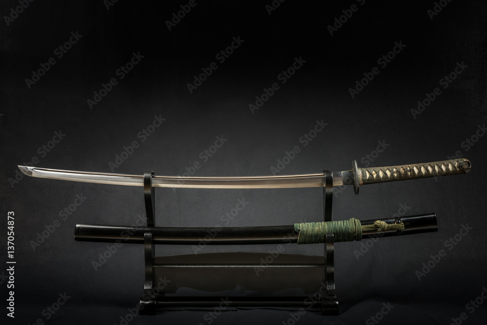 Japanese iaido sword in black wooden stand and black background. Still ...