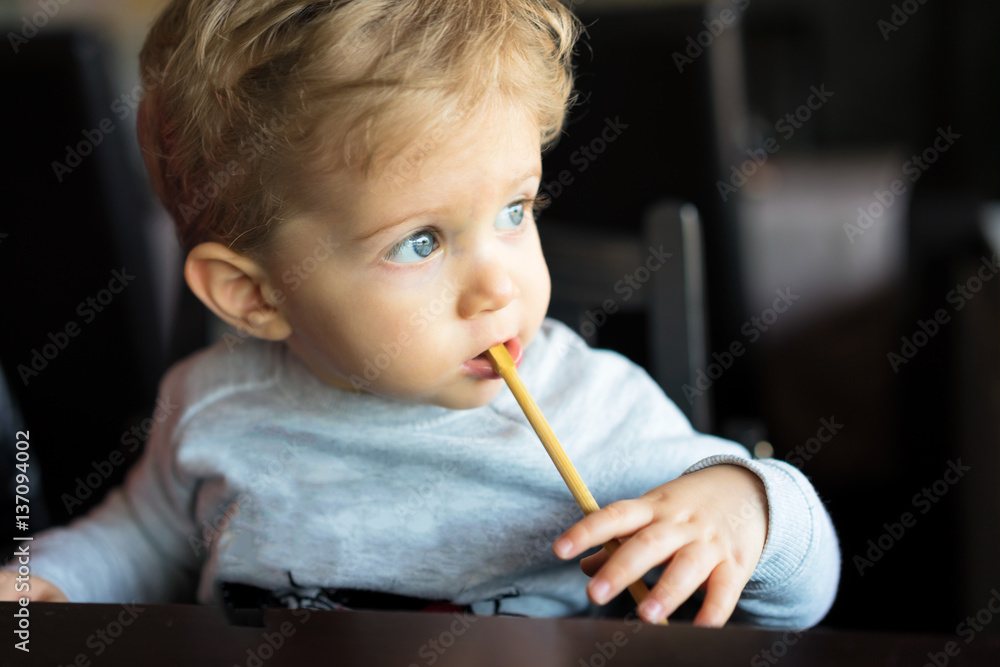 Baby boy sitting in high chair and plays with chopsticks at chinese ...
