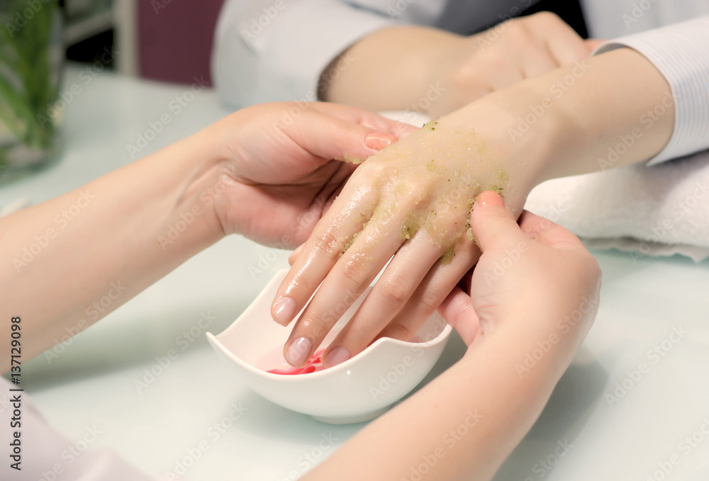 Woman hands in a nail salon receiving a hand massage by a beautician ...