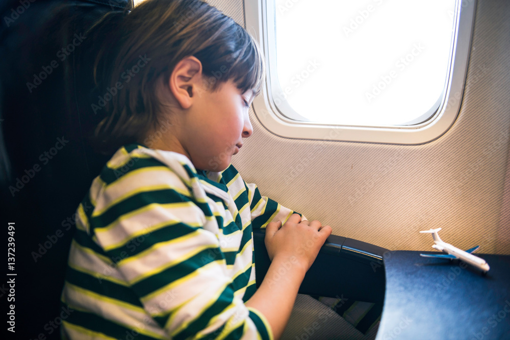 Boy on airplane asleep in airplane window seat Stock Photo | Adobe Stock