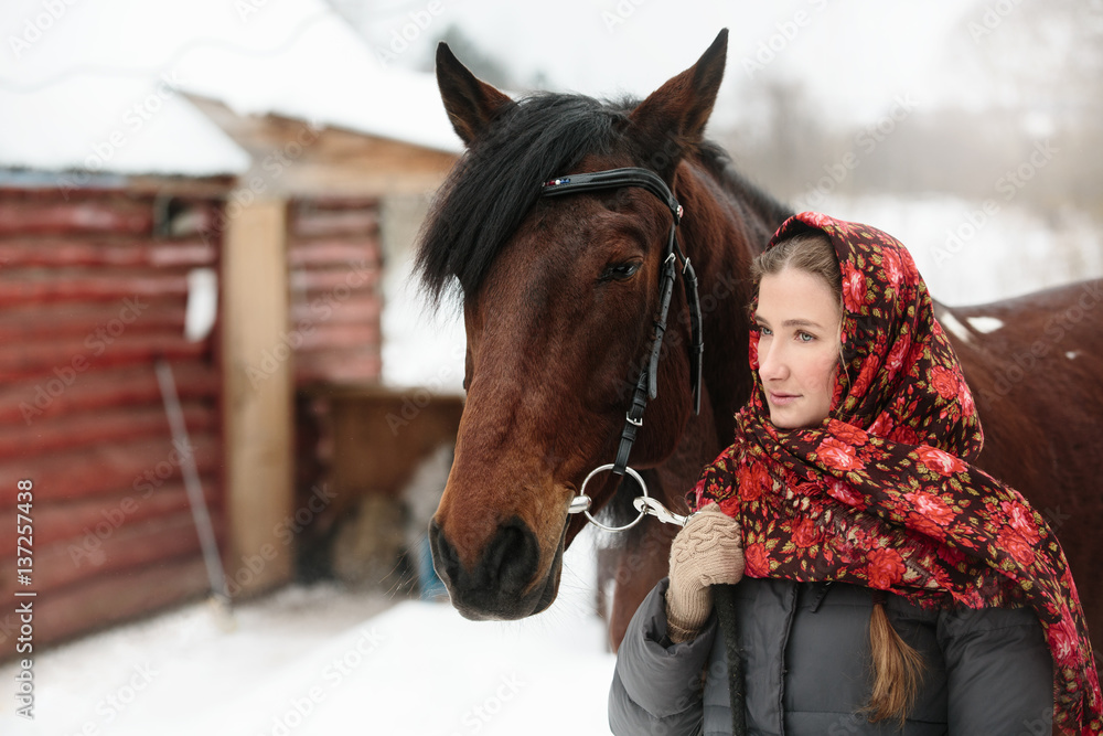 Russian Winter. Beautiful girl in a traditional scarf holding a horse ...