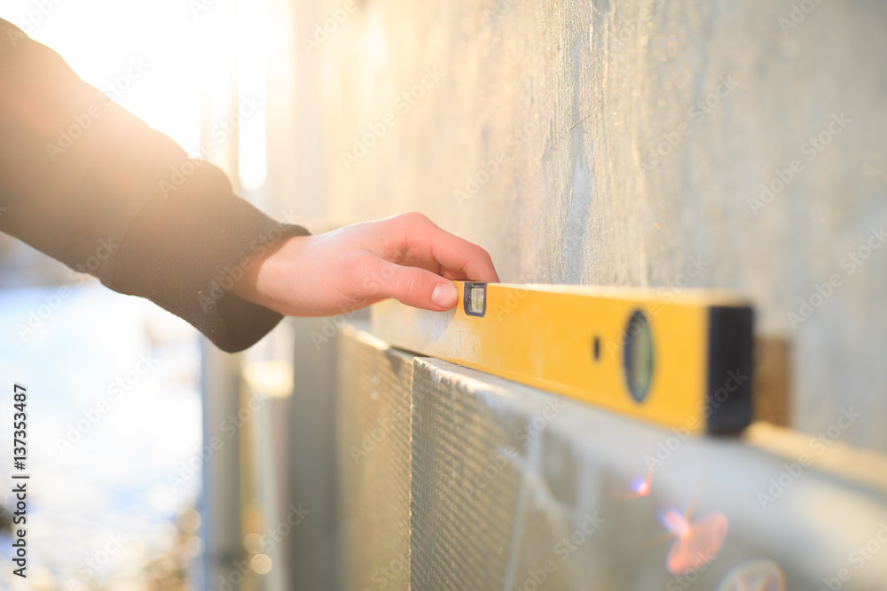 Young builder man hand measuring wall of house by professional yellow ...