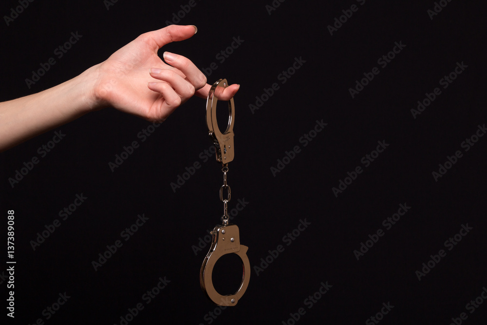 Female hand holding handcuffs on a dark background Stock Photo | Adobe ...