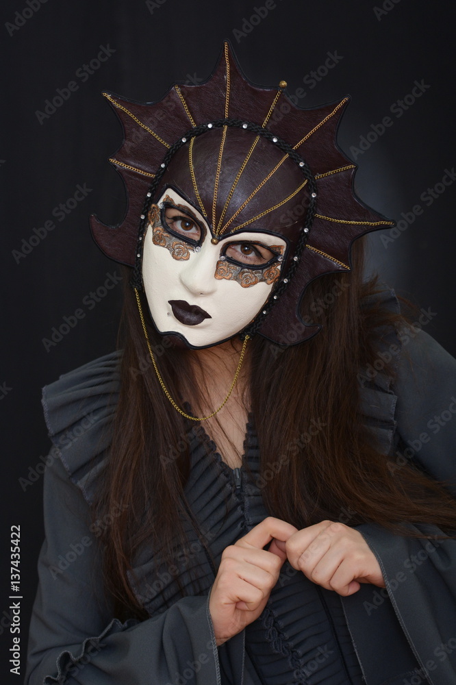 actress brunette holding an old theatrical mask in hands against a dark ...