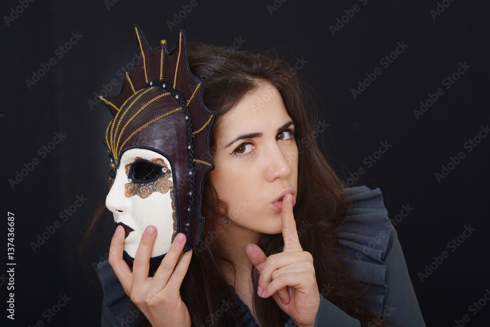 actress brunette holding an old theatrical mask in hands against a dark ...