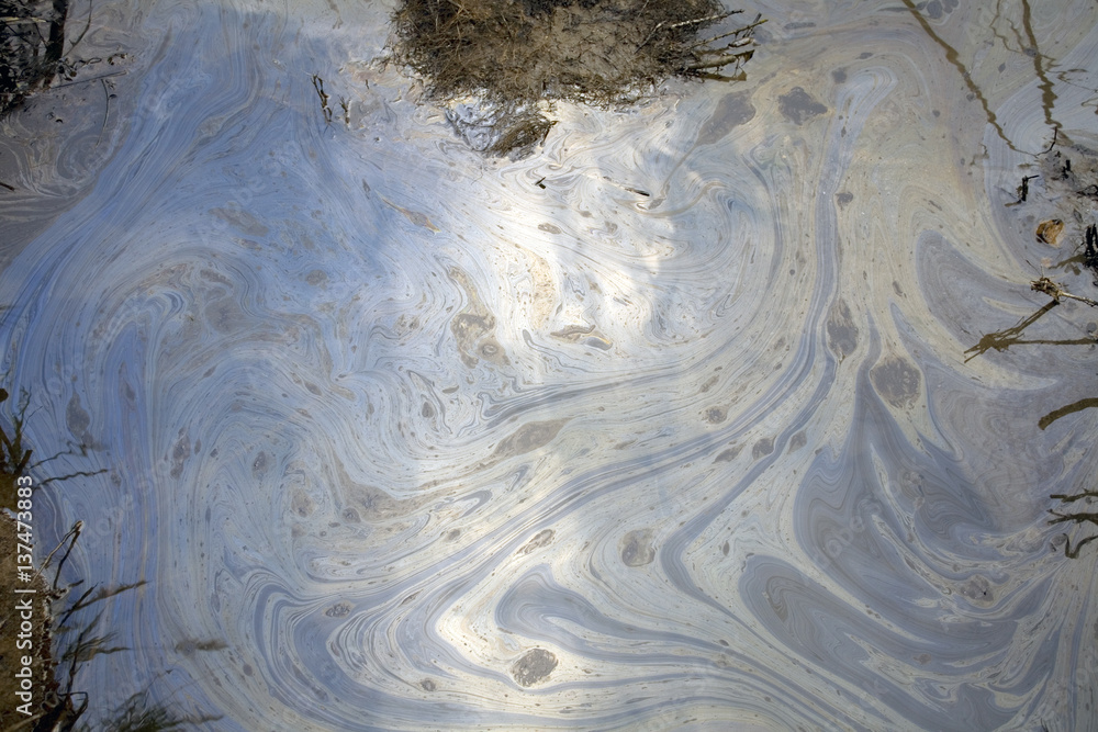Foto de Puddle of crude oil on the ground from an oil spill. do Stock ...