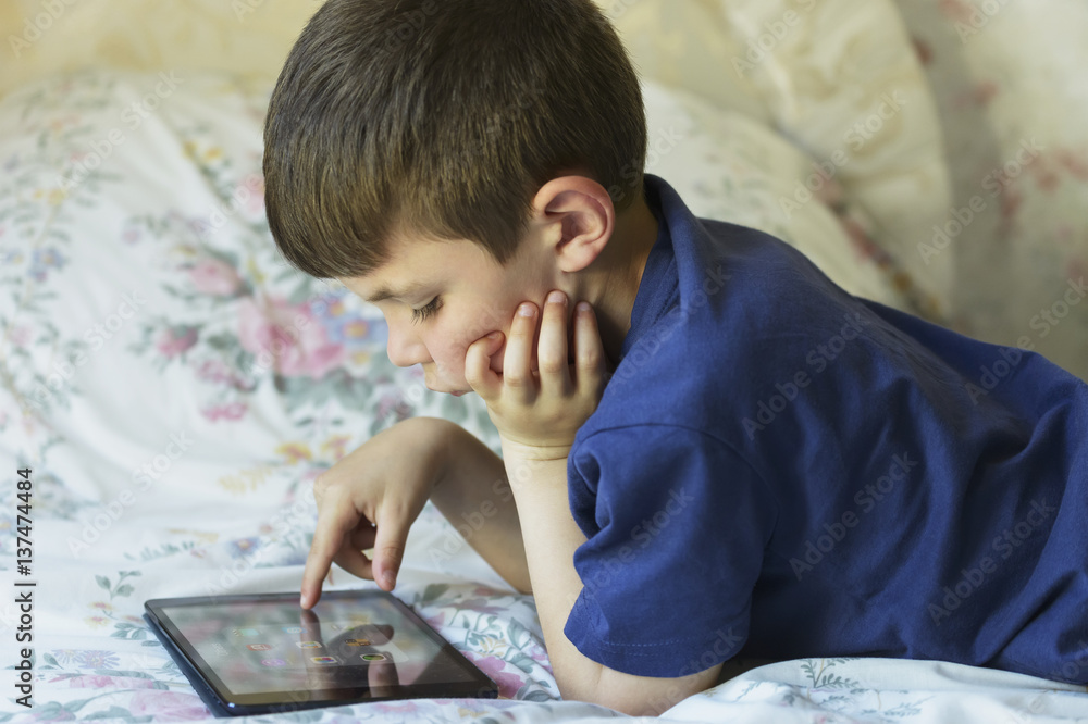 Side view of a boy using a digital computer on a bed Stock Photo ...