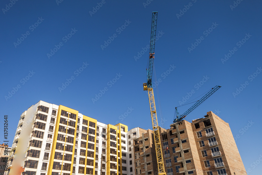 Crane and high rise building under construction against blue sky ...