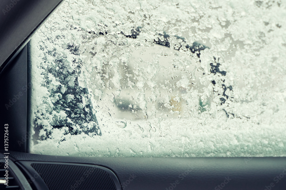 Bright background of falling snow on the windshield of the car. The ...