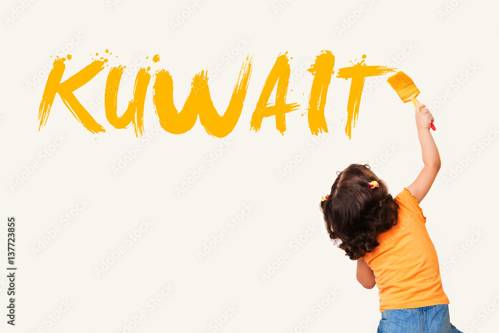 Cute little girl writing KUWAIT using painting brush on wall background ...