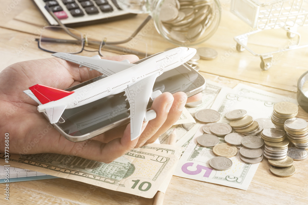 airplane model on smartphone in hand, money banknote,coins and Office ...