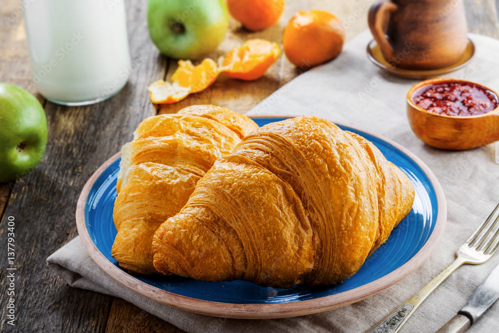 Traditional French breakfast with croissants, fruit jam and milk on a ...
