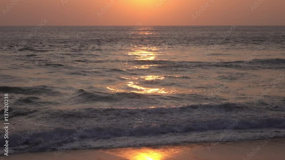Golden sun over tropical beach with its reflection on the water and ...
