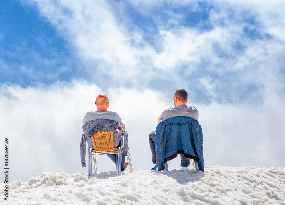 Two rich men sitting in chairs at the top of snow capped Tahtali Dag ...