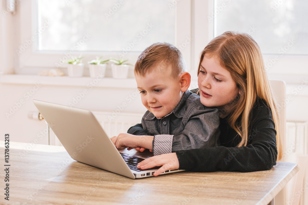 Brother and sister playing games on computer at home Stock Photo ...