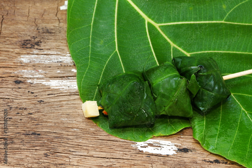 Leaf wrapped bite size appetizer with bamboo wood stick put on fresh ...